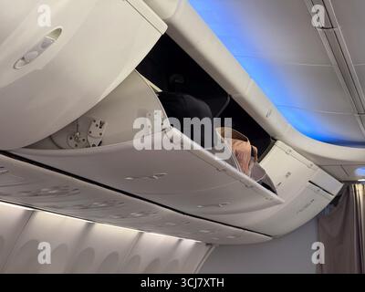 Overhead storage bins inside airplane cabin with luggage and personal ...