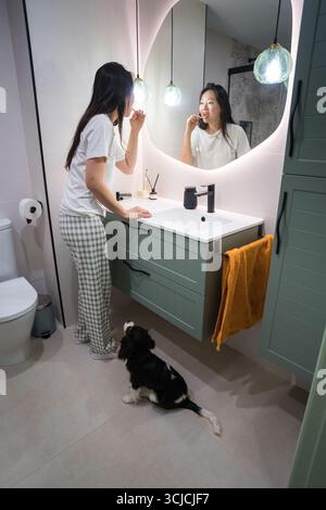 Calm Asian woman sits with her pet black and white cat on rustic wooden ...