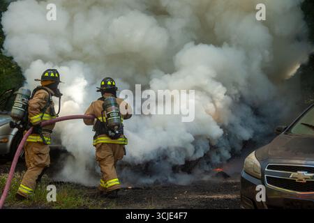 Firefighters battle a blazing car fire with heavy smoke and flames ...
