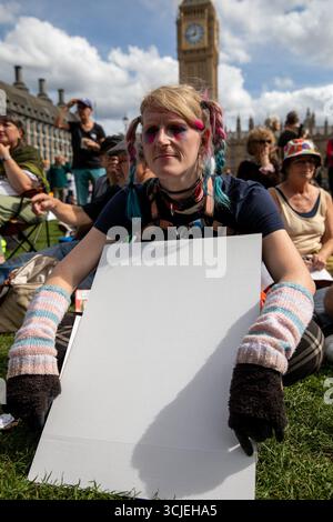 A protester sits with a placard stating 'I oppose genocide, I support ...
