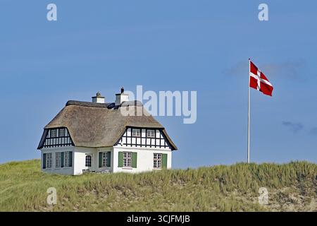 The flag of Denmark on the roof of a house overlooking the calm sea ...