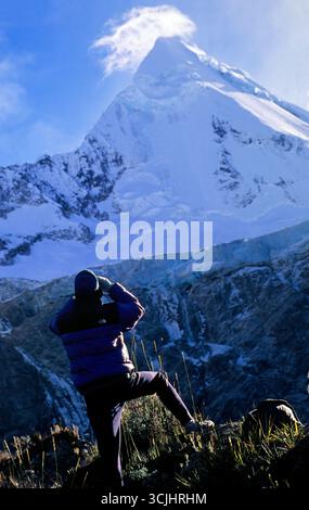 Using binoculars a single male mountain climber looks at Artesonraju 6 ...
