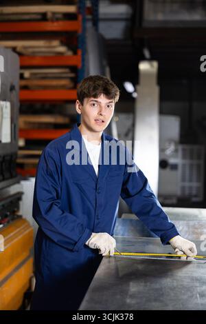 Guy measuring sheet of metal with tape measure Stock Photo - Alamy