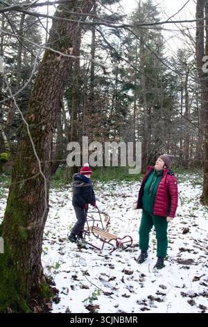 A man pulls a child in a sled during a snowfall in a park, in Bucharest ...