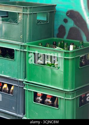 Green plastic crates with empty glass bottles on street corner ...