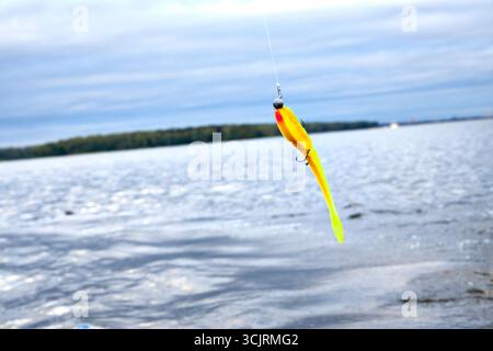 Fishing lure on the hook above the lake water Stock Photo - Alamy
