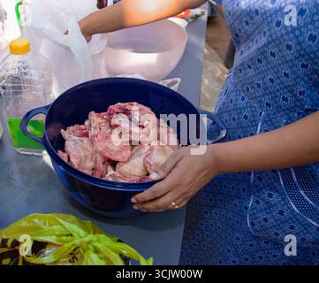 village African woman washing chicken meat in a cauldron at an event ...