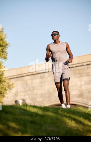Man wearing sunglasses running at public park during sunny day Stock ...