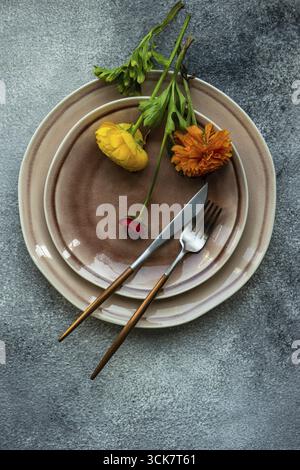 Rustic table setting with ranunculus flowers on concrete background ...