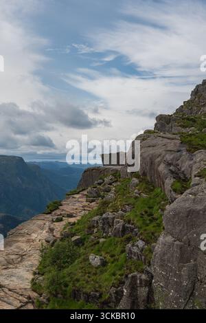 Dramatic cliffside view overlooking lush green valley under a cloudy ...