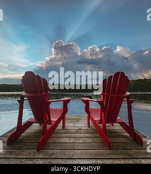 A beautiful view of two red chairs on the beach looking at the water ...