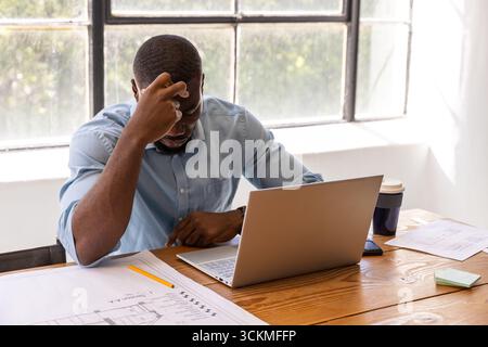 african american architect typing on laptop near notebook and green ...