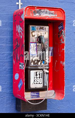 A pay phone booth covered in colorful graffiti is depicted in this ...