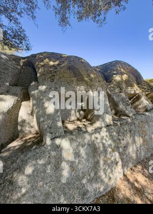 Ancient rock-cut altar with multiple niches under oak trees in Sardinia ...