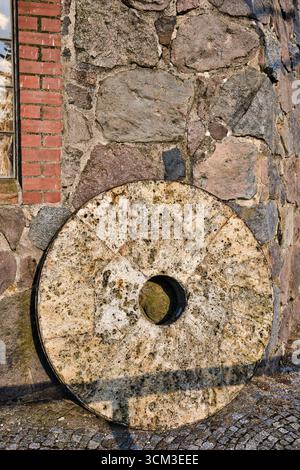 Old Millstone Leaning Against a Rustic Wall Stock Photo - Alamy