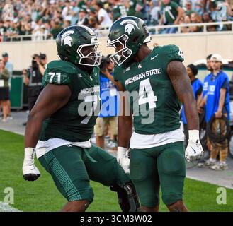 Michigan State running back Elijah Tau-Tolliver, left, tries to leap ...