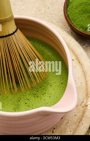Close up bamboo whisk and matcha green tea powder on black background ...