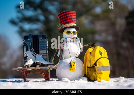Snowman standing by luggage outdoor. Winter vacation. Christmas and New ...