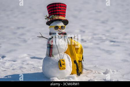 Snowman standing by luggage outdoor. Winter vacation. Christmas and New ...