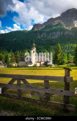 The towering cliffs of the Dolomites in Italy rise above dense green ...