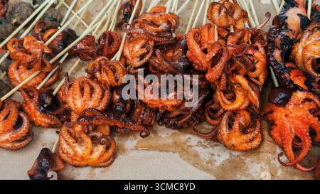 Grilled octopus skewers with curled tentacles displayed as traditional ...