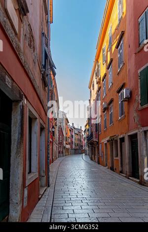 Narrow historic street lined with colorful pastel houses and blue ...