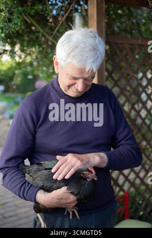Senior man with hen in farm yard Stock Photo - Alamy