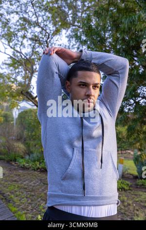 Casual adult in grey hoodie sitting indoors and scrolling smartphone ...