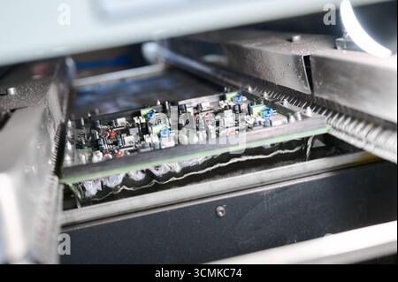 Wave soldering process for PCB tinning in a molten solder bath at a ...