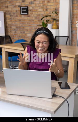 Modern laptop, houseplants on table and sticky notes on white wall ...