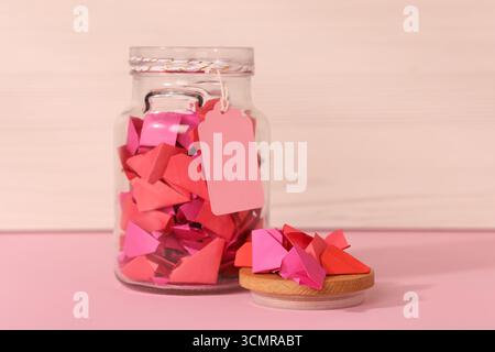 Color paper pieces in glass jar on pink table, space for text Stock ...