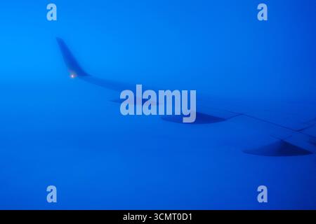 Commercial passenger airplane viewed from below against a blue sky with ...