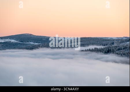 Winter inversion sunset with snow covered hills and forests rising ...