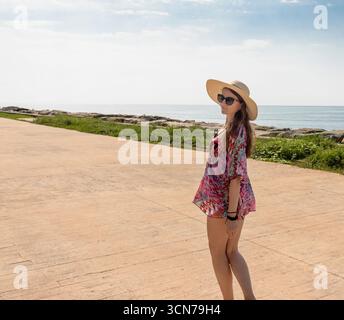 Shot of an attractive woman wearing straw hat and sunglasses while ...