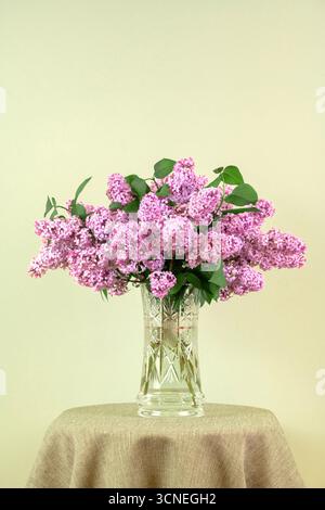 Vase with lilac flowers and cloth on table in living room Stock Photo ...