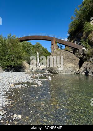 A beautiful scenery of narrow wooden bridge over river in a park during ...