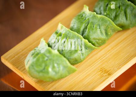 Raw and cooked Japanese gyoza dumplings on rustic surfaces – handmade ...