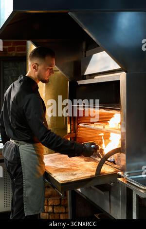 Young male cook working in the kitchen Stock Photo - Alamy