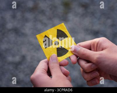 A young man holding a radiation warning sign in his hands. Close up ...