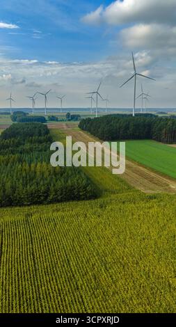 The wind turbines surrounded by dense green trees against a cloudy sky ...