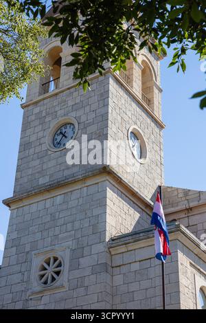 A historic stone church tower rises above medieval walls and terracotta ...