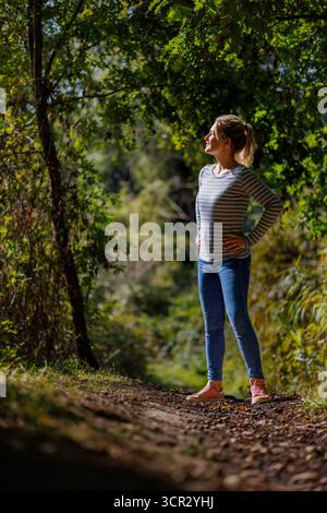 Portrait of woman wearing striped T-shirt holding laptop and pointing ...