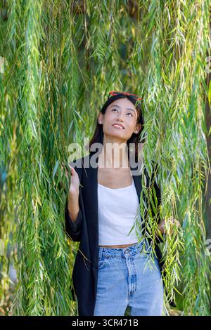 Mature woman standing under willow tree Stock Photo - Alamy