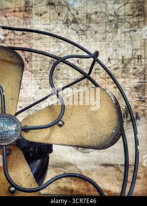 Antique metal fan with old map in the background jn black and white ...