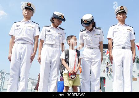 A boy interacting with PLA officers on the deck of the Chinese PLA Navy ...