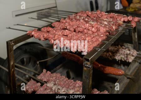 Juicy meat rolls cooking on metal skewers over hot charcoal with ...