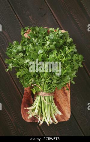 A fresh bunch of vibrant green cilantro, or coriander, lies on a light ...