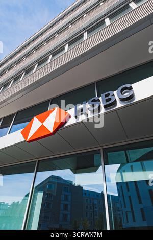 Facade of HSBC bank branch with red and white logo on concrete office ...