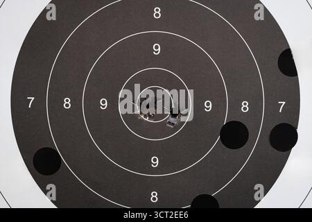 Paper target with tight bullet holes group hanging on wooden bullet ...