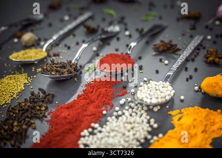 Collection of spices are spread out on a table. The spices include ...